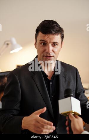 Portrait of entrepreneur giving interview to TV anchor about his new ...