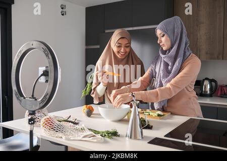Two muslim food vloggers making a video while prepping vegetables in ...