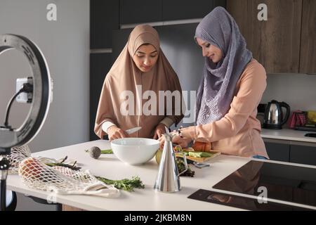 Two muslim food vloggers making a video while prepping vegetables in ...