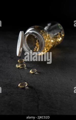 Vitamin D caps out of the container on a dark background Stock Photo ...
