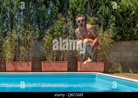 Middle-aged man cannonball dives into swimming pool shouting Stock ...