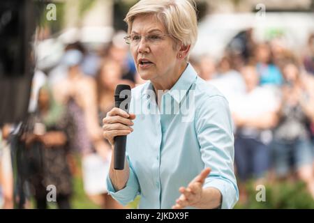 Democratic Senator Elizabeth Warren holds a microphone and speaks at an ...