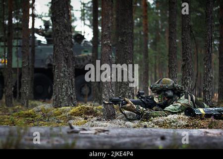 A Finnish Soldier assigned to Jaeger Brigade, assists a U.S. Army ...