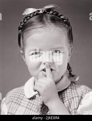 Portrait of little girl gesturing shush Stock Photo - Alamy