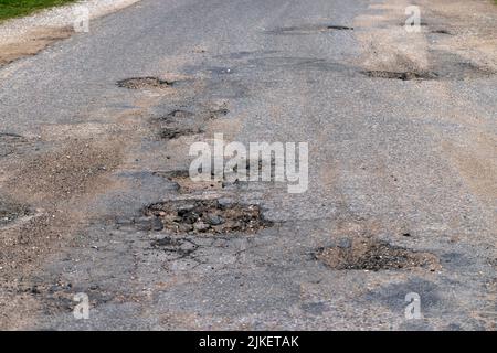 poor paved road with a lot of holes and potholes, poor transport ...