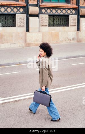 woman crossing the street and talking by phone Stock Photo - Alamy