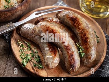 Closeup of fried bratwurst garnished with thyme on a plate on a rustic ...
