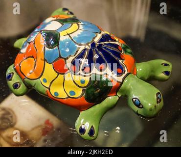 A closeup shot of a small colorful turtle toy in the muddy ground near ...