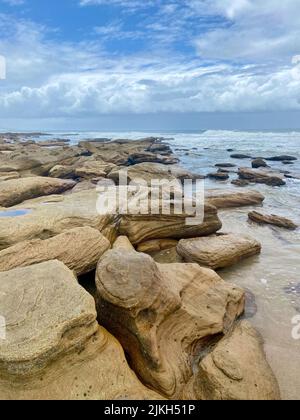 A vertical shot of a rocky beach against a sea covered with fog Stock ...