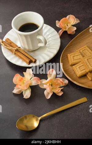 Cup of coffee with pastries decorated with spring flowers on dark ...