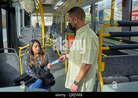 A male suggesting mask to a female passinger sitting in a bus Stock ...