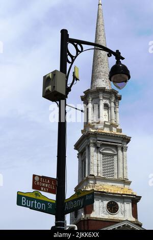A vertical shot of a street lamp in front of a mountain slope covered ...