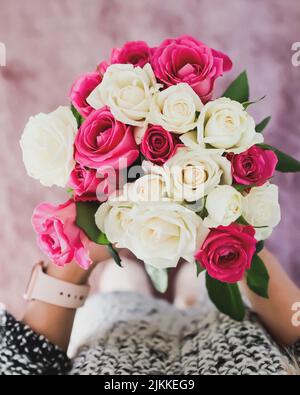 A vertical shot of a bouquet of bright flowers in a glass vase isolated ...