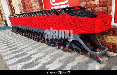 Row of red plastic shopping carts parking in the supermarket. Concept ...