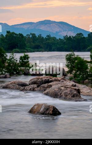 A long exposure shot of a river flowing over rocks in a forest covered ...