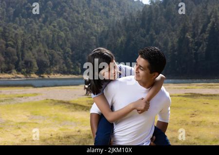 A Spanish father and daughter playing outdoors and piggyback posing in ...