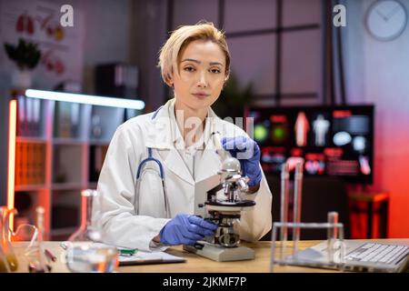 Attractive young female scientist supervisor using microscope research in laboratory ...