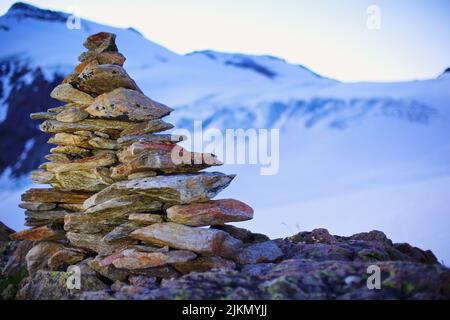 A selective focus of a pile of rocks on the coast, with calm sea in the ...
