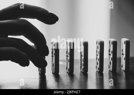 Woman's hand and dominoes on the table in the dark, domino effect ...