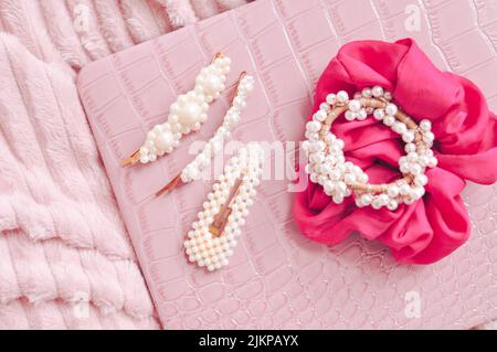 Set of pearl hairpins and elastic bands on pink background . High ...