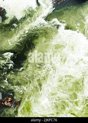 A vertical top shot of foamy waves covering some stones Stock Photo - Alamy