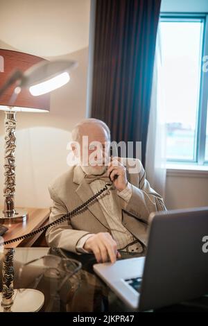 A gray-haired gentleman calling to the room service Stock Photo - Alamy