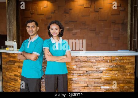 two receptionists wearing turquoise uniforms smiling with welcome hands ...