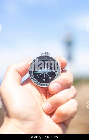 Closeup, hand holding an analog compass on the beach in front of the ...