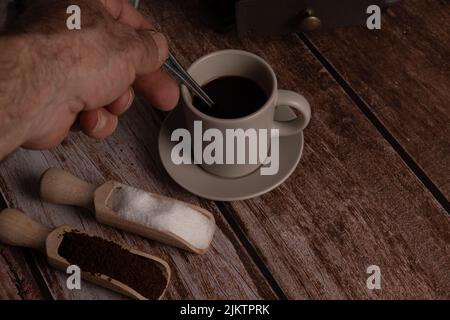 Man's hand with a spoon twirling coffee with two wooden spoons with ...