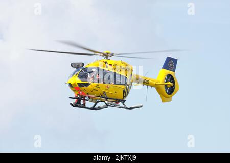 Yellow ADAC rescue helicopter hovering in the air, front view. German ...