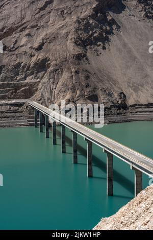 Vertical shot of a bridge over hills with mountains covered in snow on ...