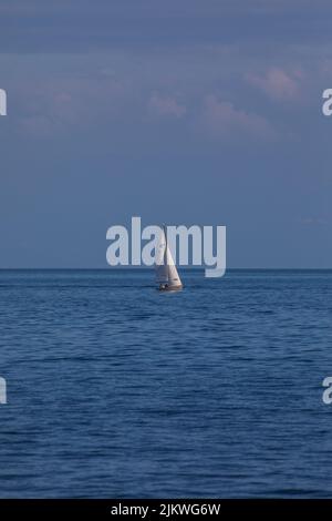 A vertical shot of a ship floating in the ocean on a sunny day in ...