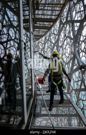 A vertical shot of men cleaning the windows of towers in Doha, Qatar ...