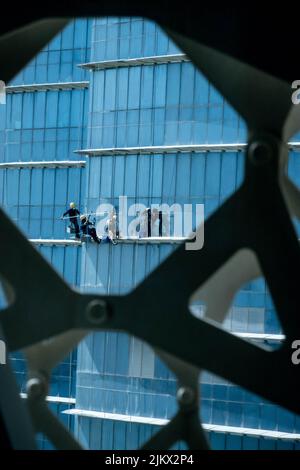 A vertical shot of men cleaning the windows of towers in Doha, Qatar ...