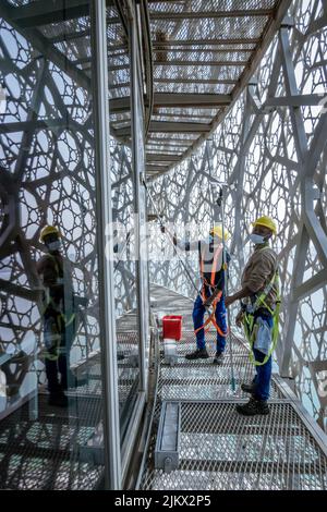 A vertical shot of men cleaning the windows of towers in Doha, Qatar ...