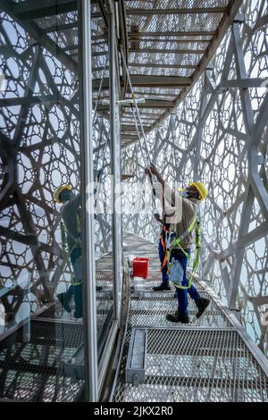 A vertical shot of men cleaning the windows of towers in Doha, Qatar ...