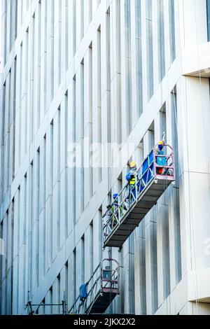 A vertical shot of men cleaning the windows of towers in Doha, Qatar ...