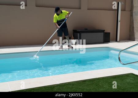 Operator cleaning a swimming pool with a butterfly trap, with ...