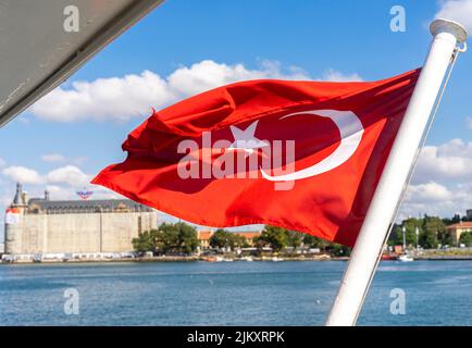 The Turkish national flag waving on a flagpole over the blue waters of ...