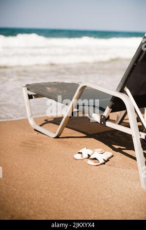 Summer slippers on the beach near the water. Sea shells on a sunny day ...