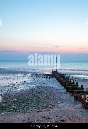 Sea groynes and reflected light over Hunstanton beach at sunset Stock ...
