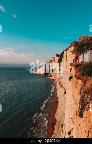 A vertical shot of a seascape with cliffs and trees under the clouds ...