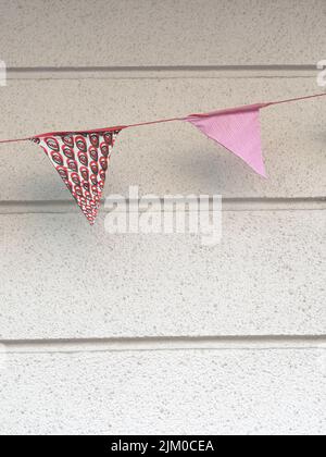Buntings with colorful triangular flags hanging on pink background ...