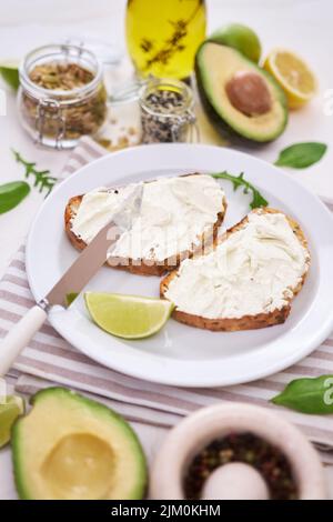 Avocado and cream cheese toasts preparation - Woman smearing cheese on ...