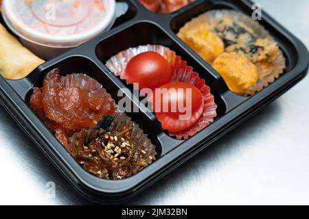 A delicious-looking lunch box with a variety of side dishes, fruits and ...