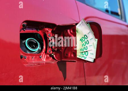 A bundle of fifty euro banknotes sticking out of a car fuel tank filler ...