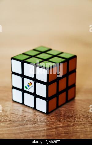 A solved Rubik cube standing on a shiny wooden surface Stock Photo - Alamy