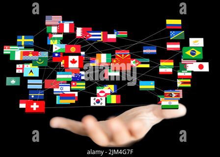 A hand holding illustrated flags of various countries on a dark ...