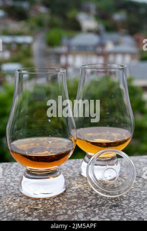 Two drams of scotch whiskey with view on old houses on background ...