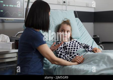 Caring mother talking with hospitalized ill daughter resting in ...